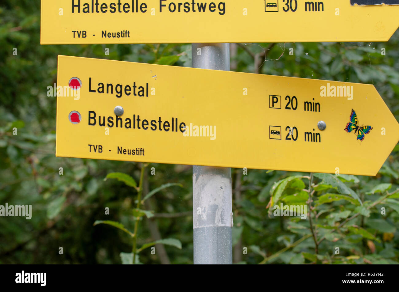 Yellow hiking trail signs, with directions and estimated time to arrive ...