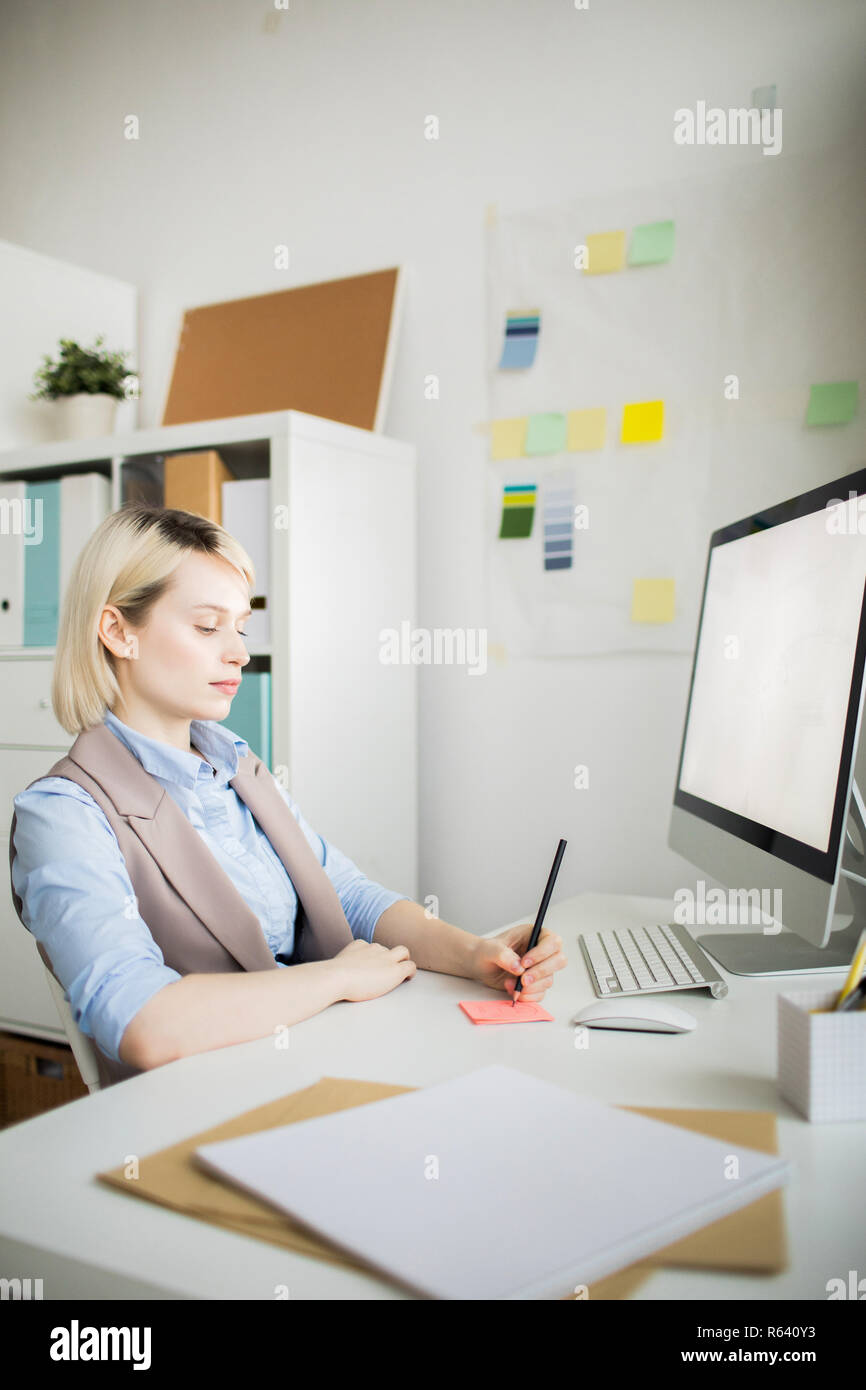 Lady manager making notes on sticker Stock Photo - Alamy