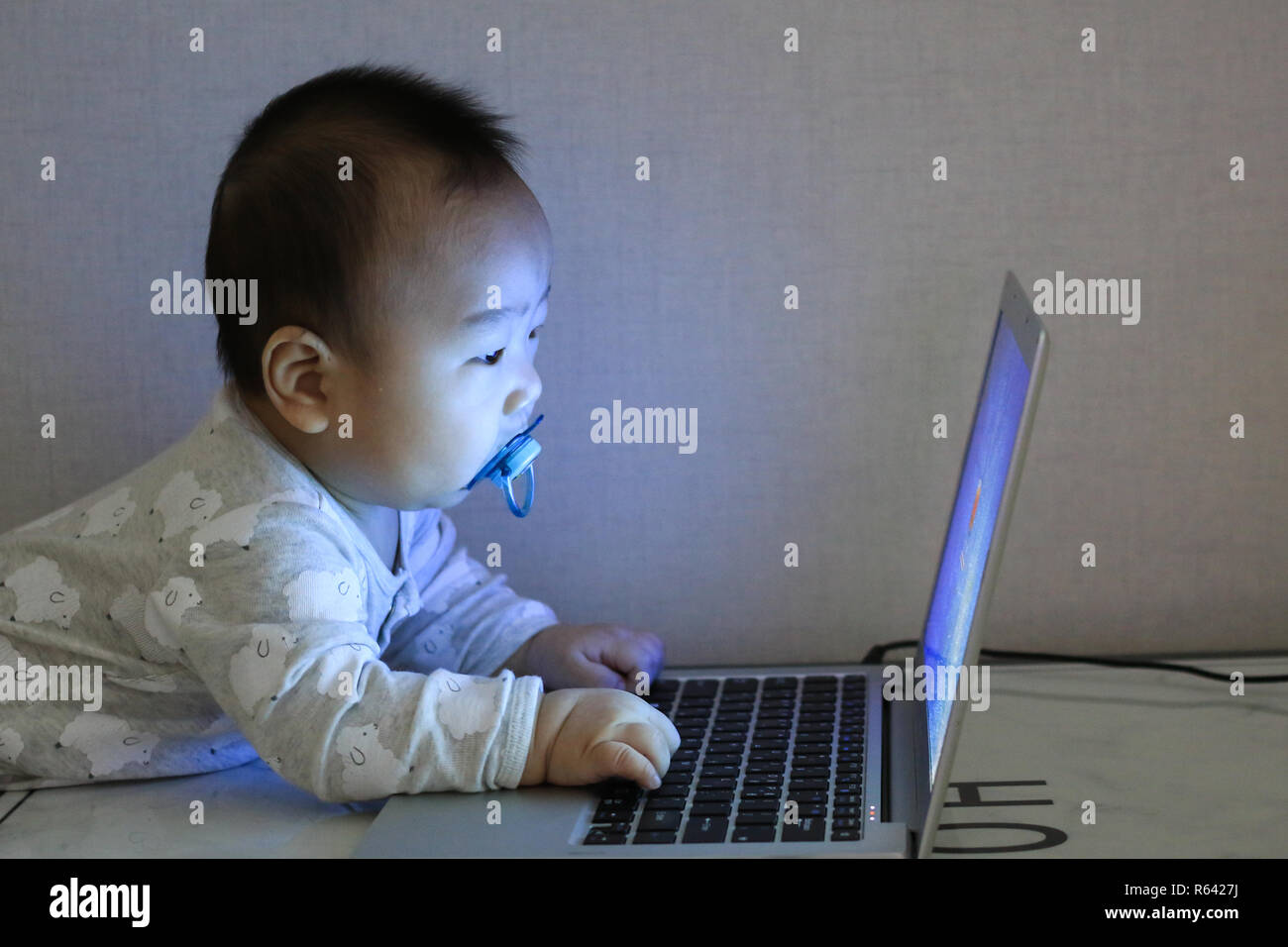 asian baby working with laptop in the darkness Stock Photo - Alamy