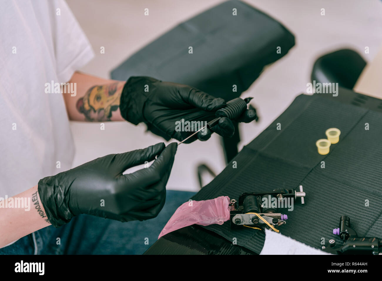 Professional tattoo master setting needle inside of tattoo machine ...