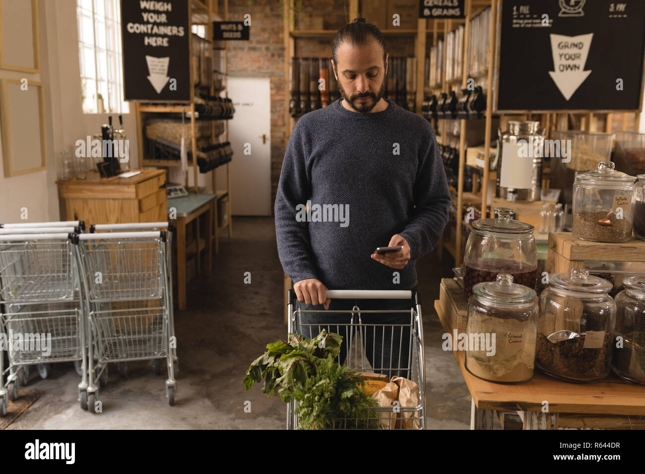 Man using mobile phone while shopping in supermarket Stock Photo - Alamy