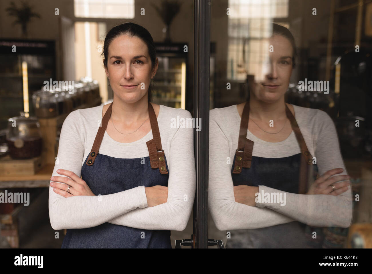 Female staff standing with arms crossed in supermarket Stock Photo - Alamy