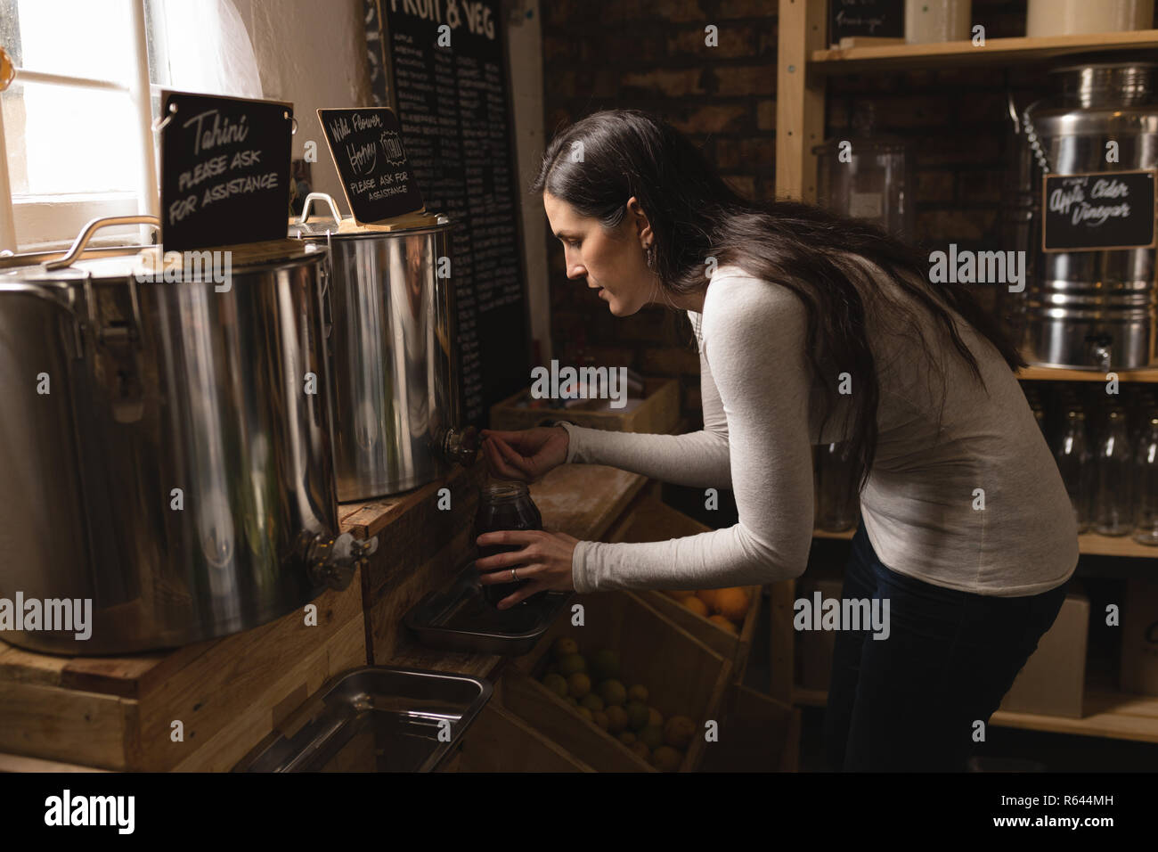 Woman filling condiment in jar at supermarket Stock Photo - Alamy
