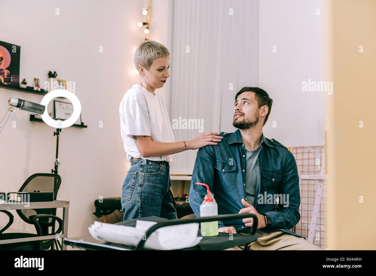 Pleasant short-haired tattoo master calming down her client Stock Photo ...