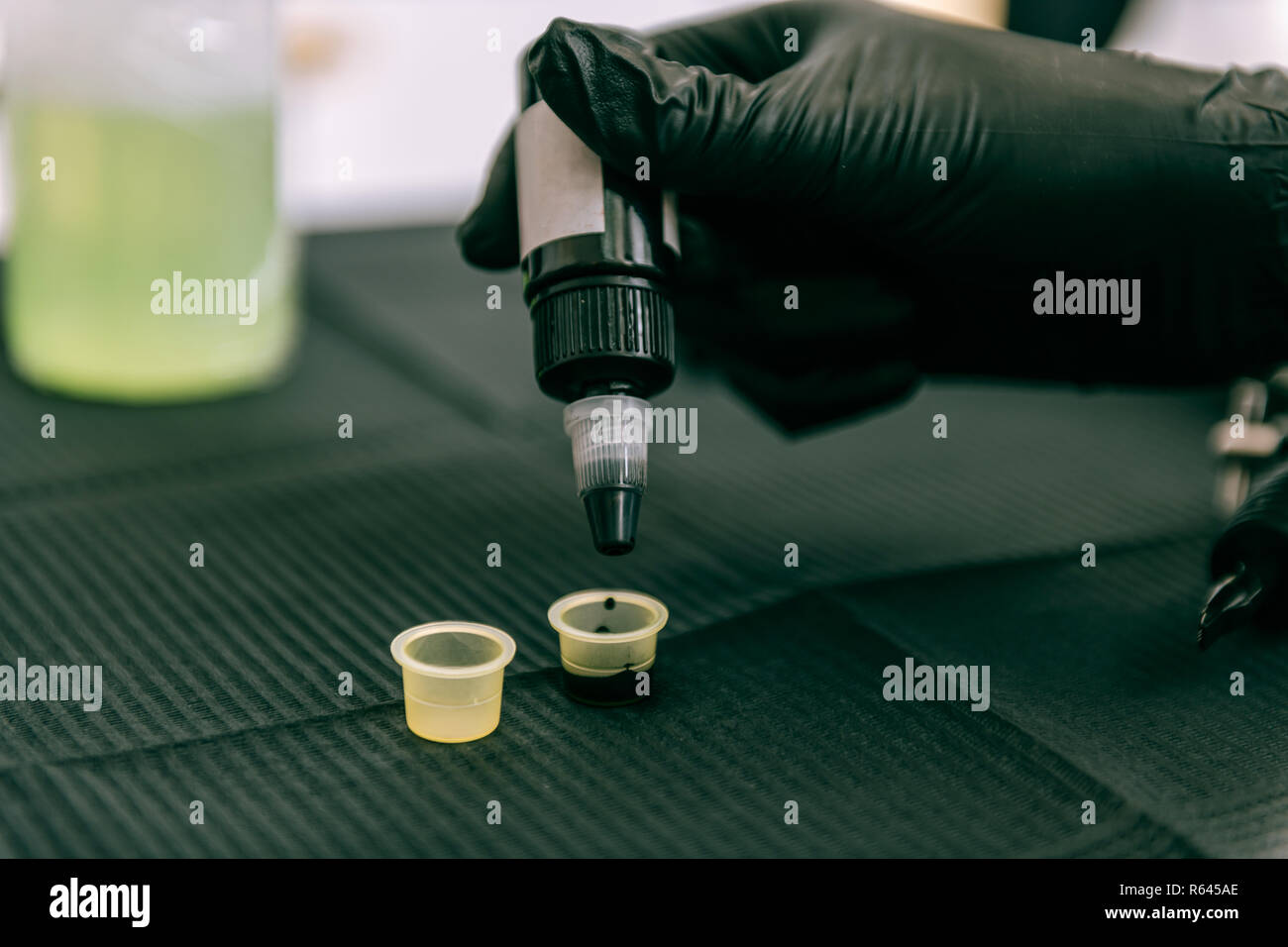 Hand covered in black rubber gloves pouring out ink Stock Photo - Alamy