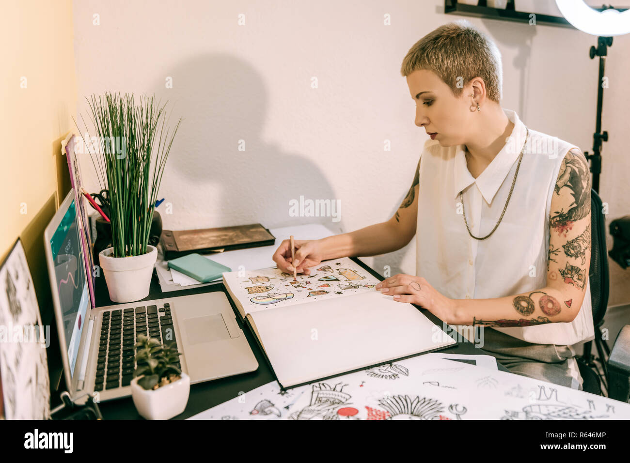 Good-looking blonde artist painting new sketches in her album Stock ...