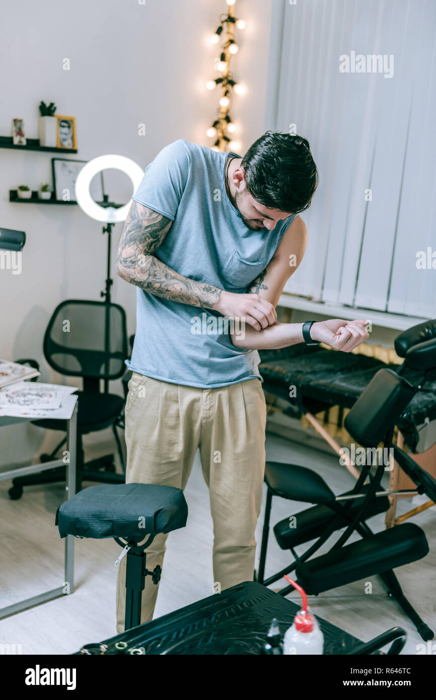 Dark-haired man observing his freshly-made tattoo on his wrist Stock ...