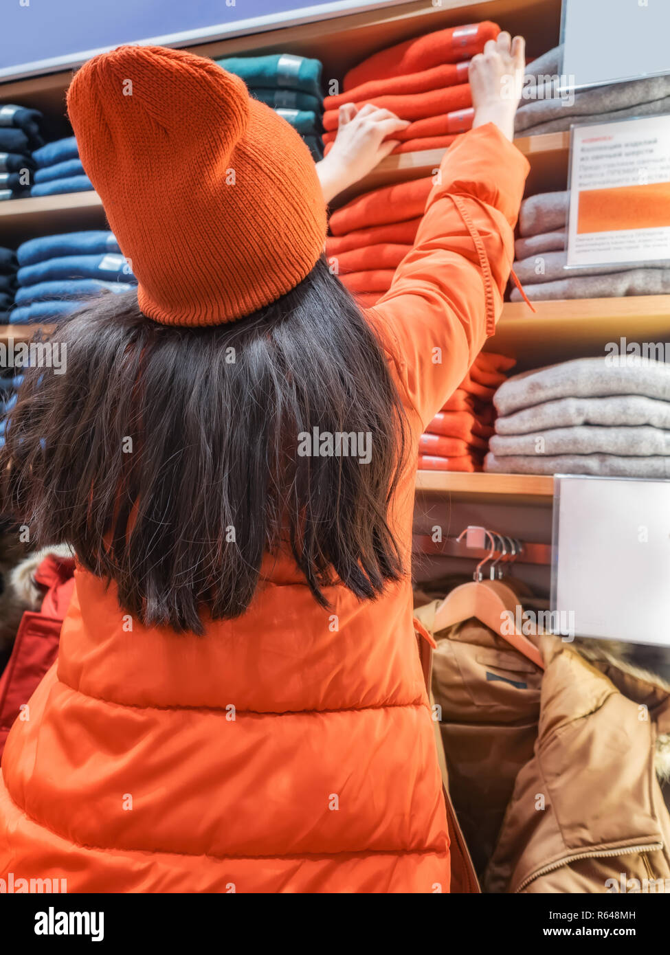 The girl holds out her hand for clothes on the store shelf. shopper ...