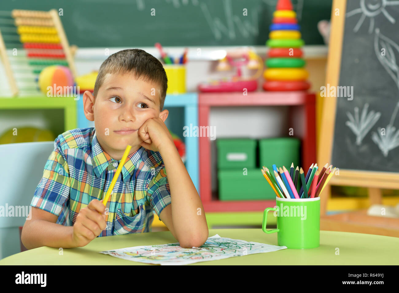 Cute little boy drawing with pencils in classroom Stock Photo - Alamy