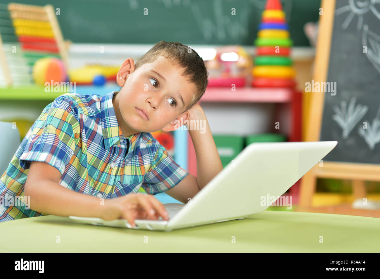Portrait of cute little boy using laptop in classroom Stock Photo - Alamy