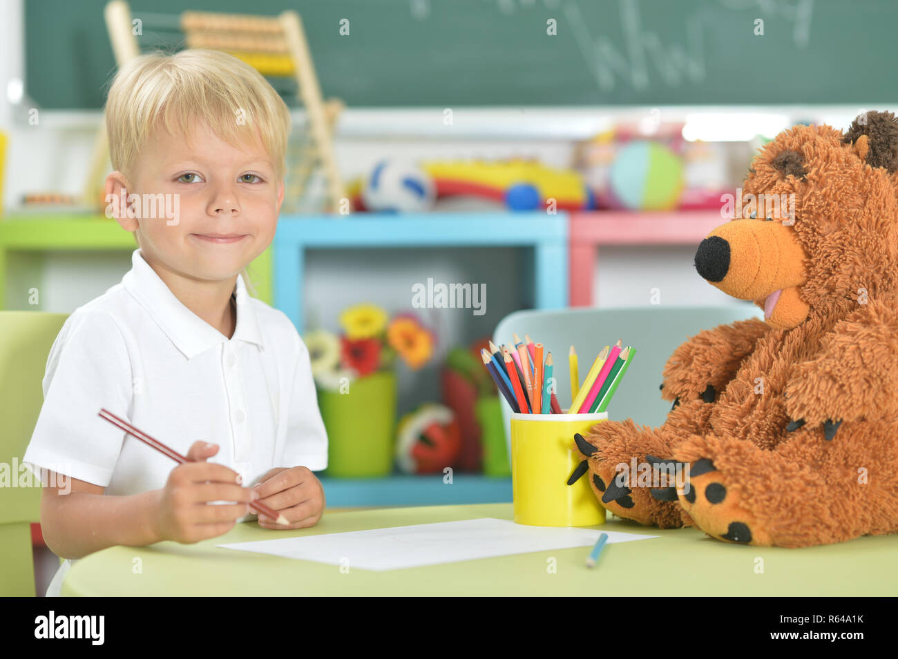Portrait of little boy drawing with pencils in classroom Stock Photo ...