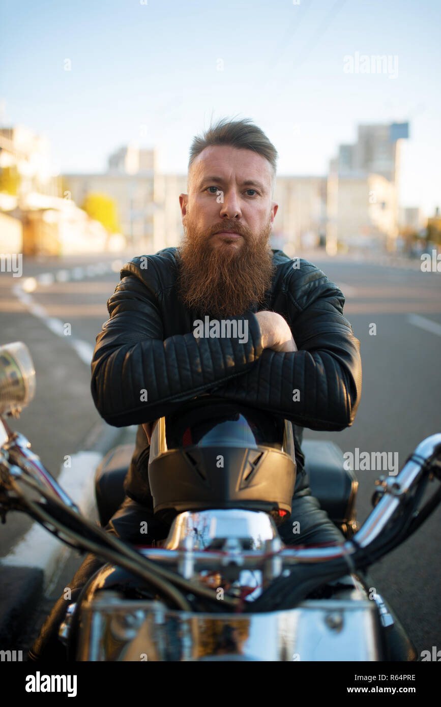 Bearded biker in leather jacket sitting on classical chopper, front ...