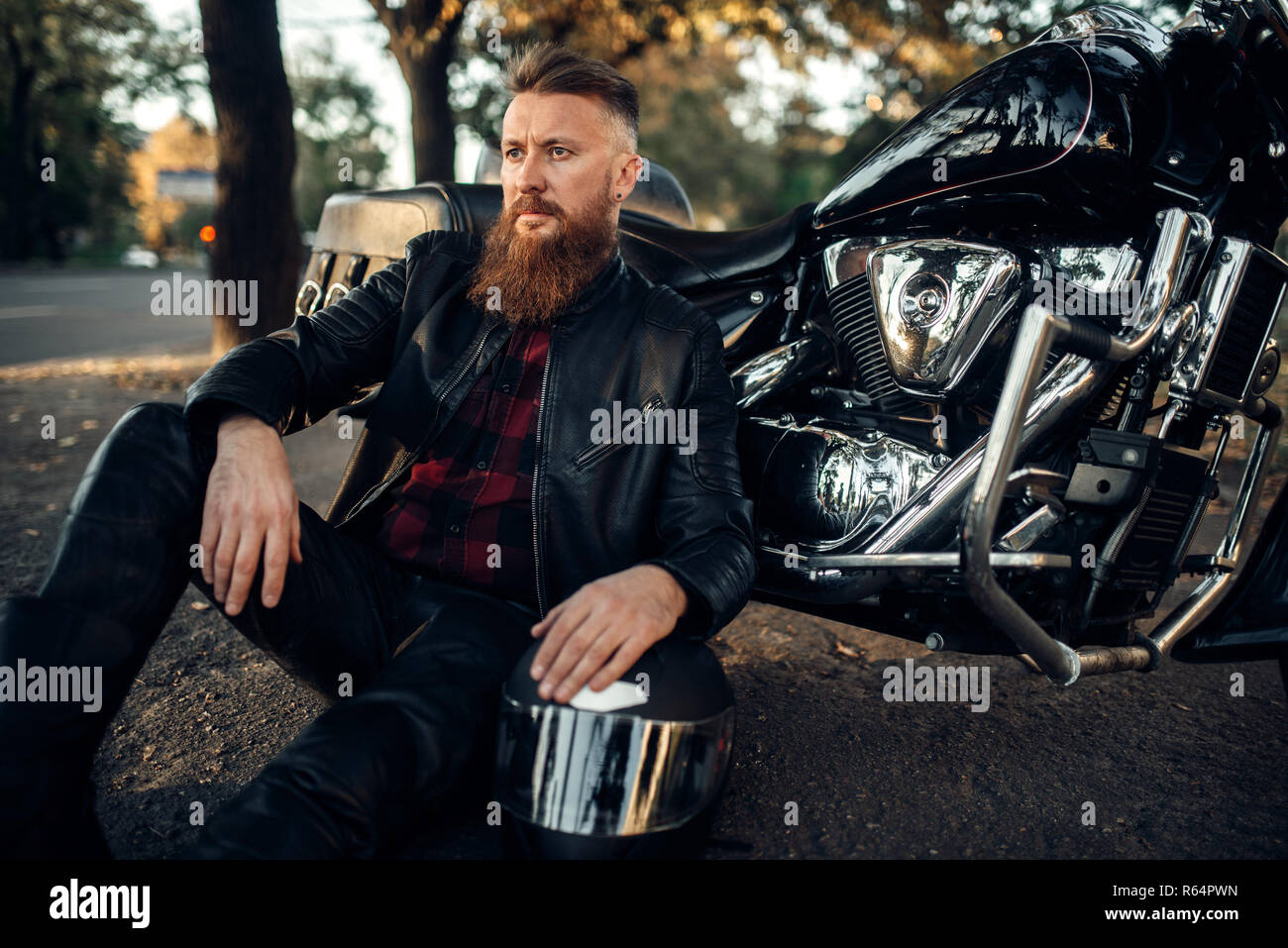 Biker in leather jacket relax after road travel on his chopper. Vintage ...