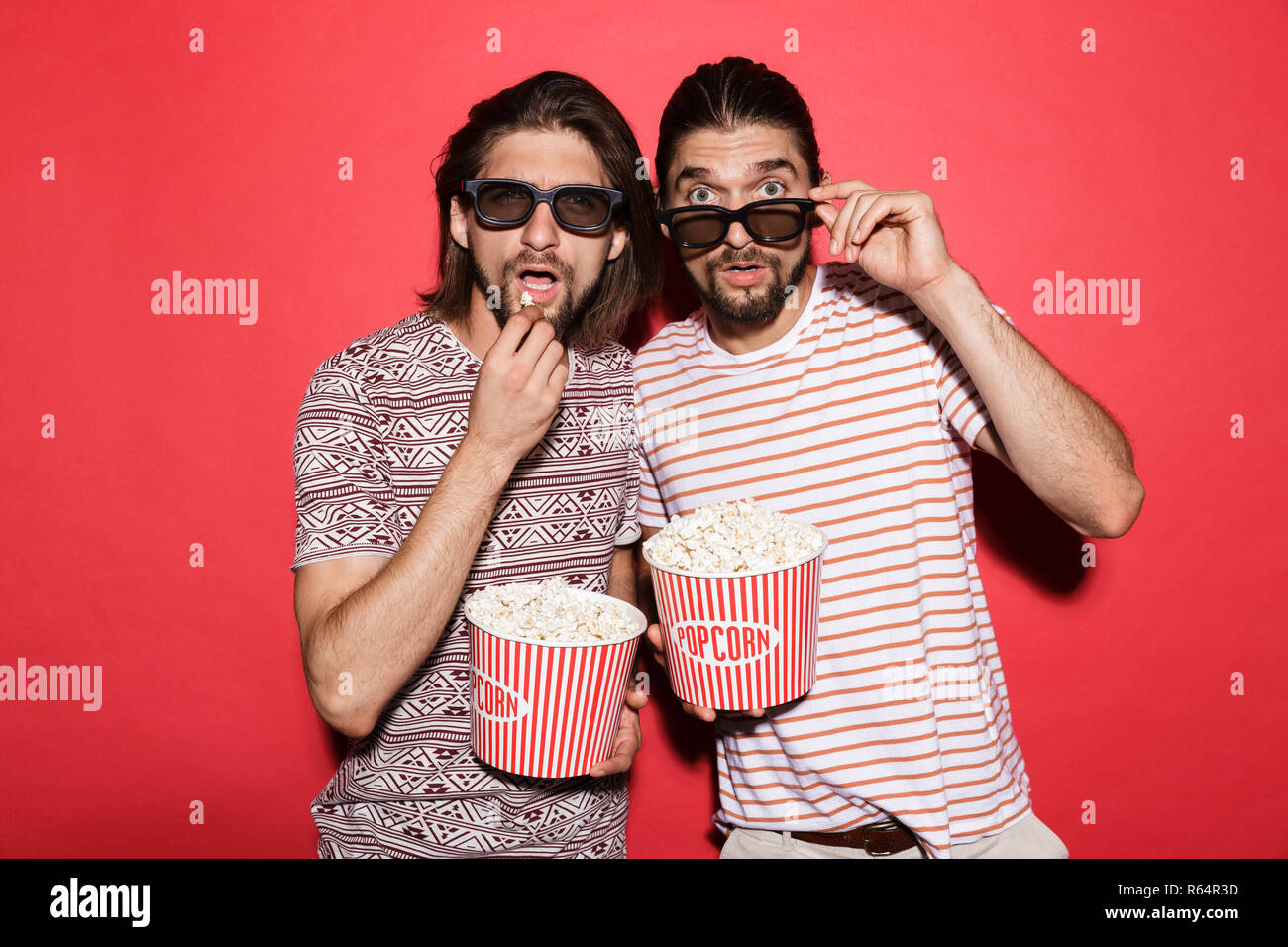 Portrait of a two young frightened twin brothers isolated over red ...