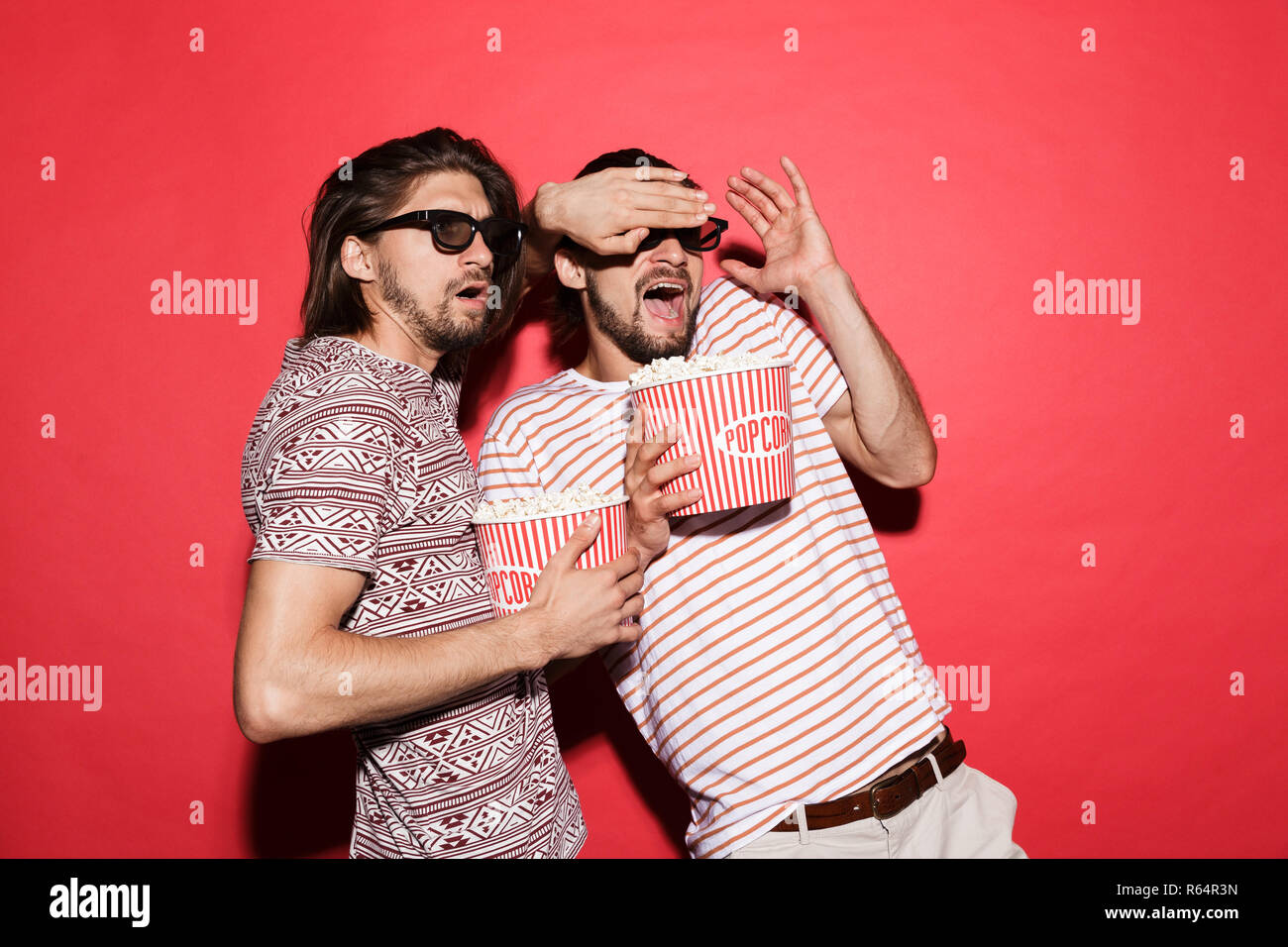 Portrait of a two young frightened twin brothers isolated over red ...