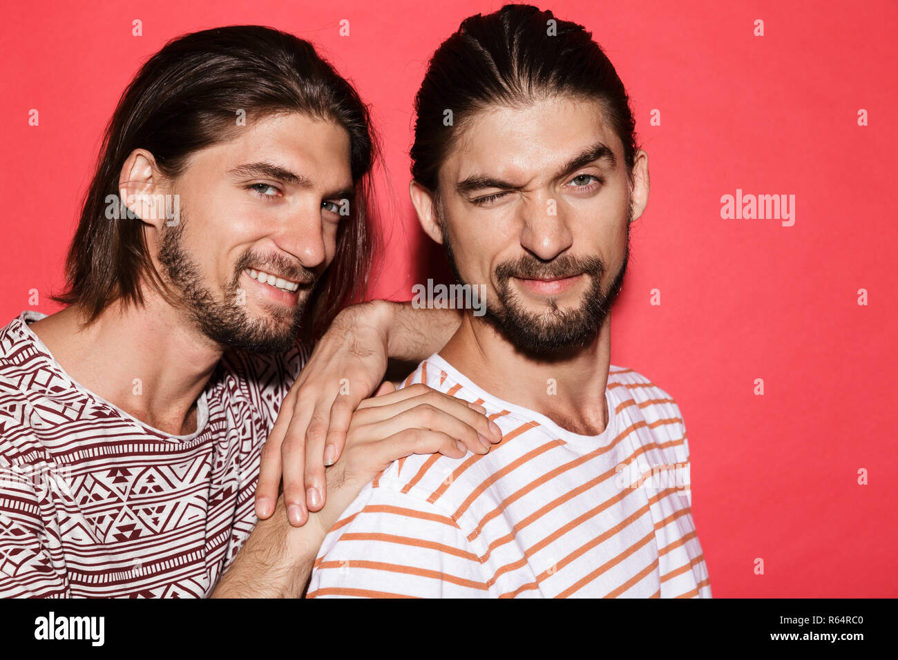 Portrait of a two young handsome twin brothers isolated over red ...