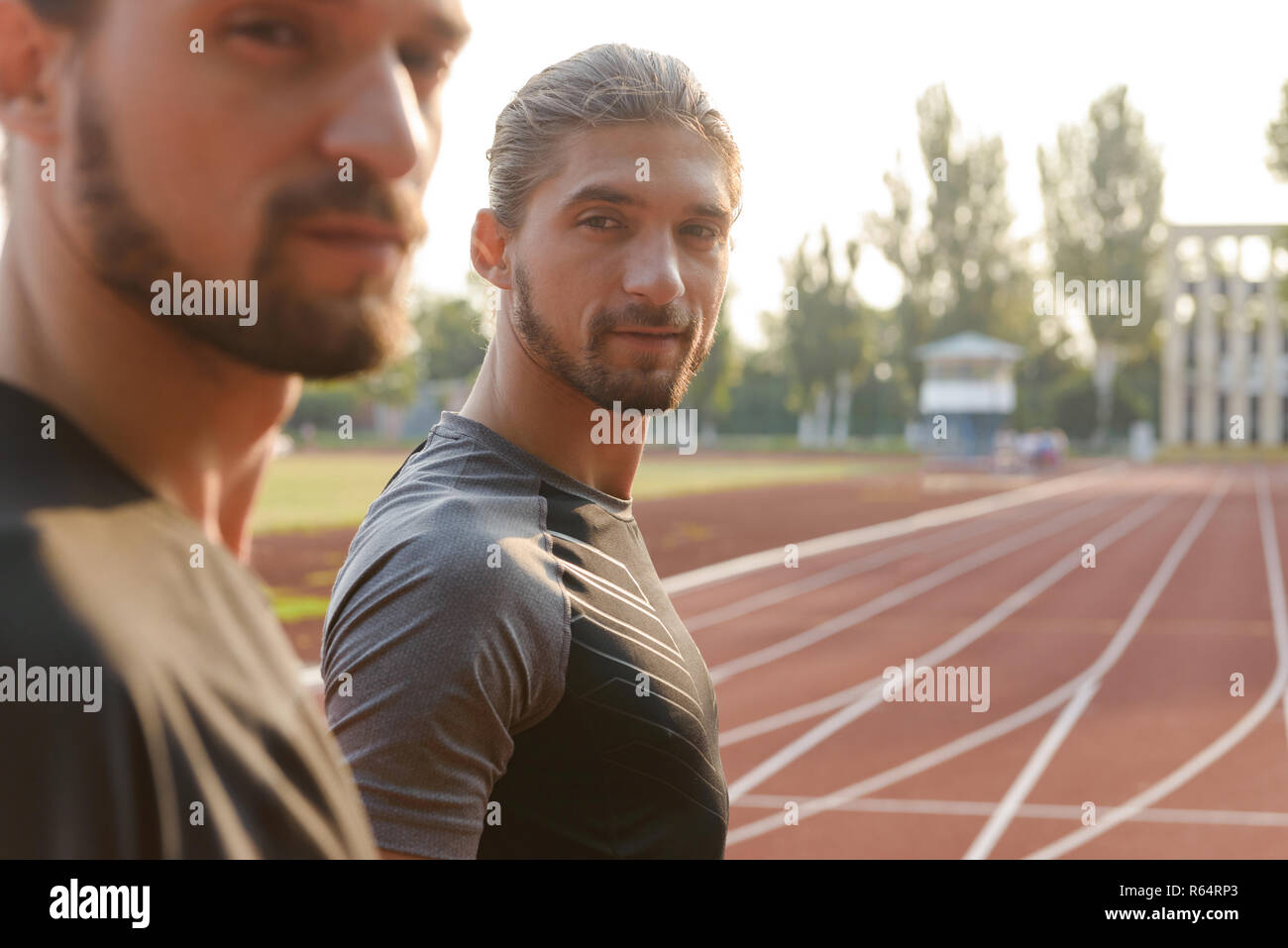 Photo of young two twins sportsmen brothers standing at the stadium ...