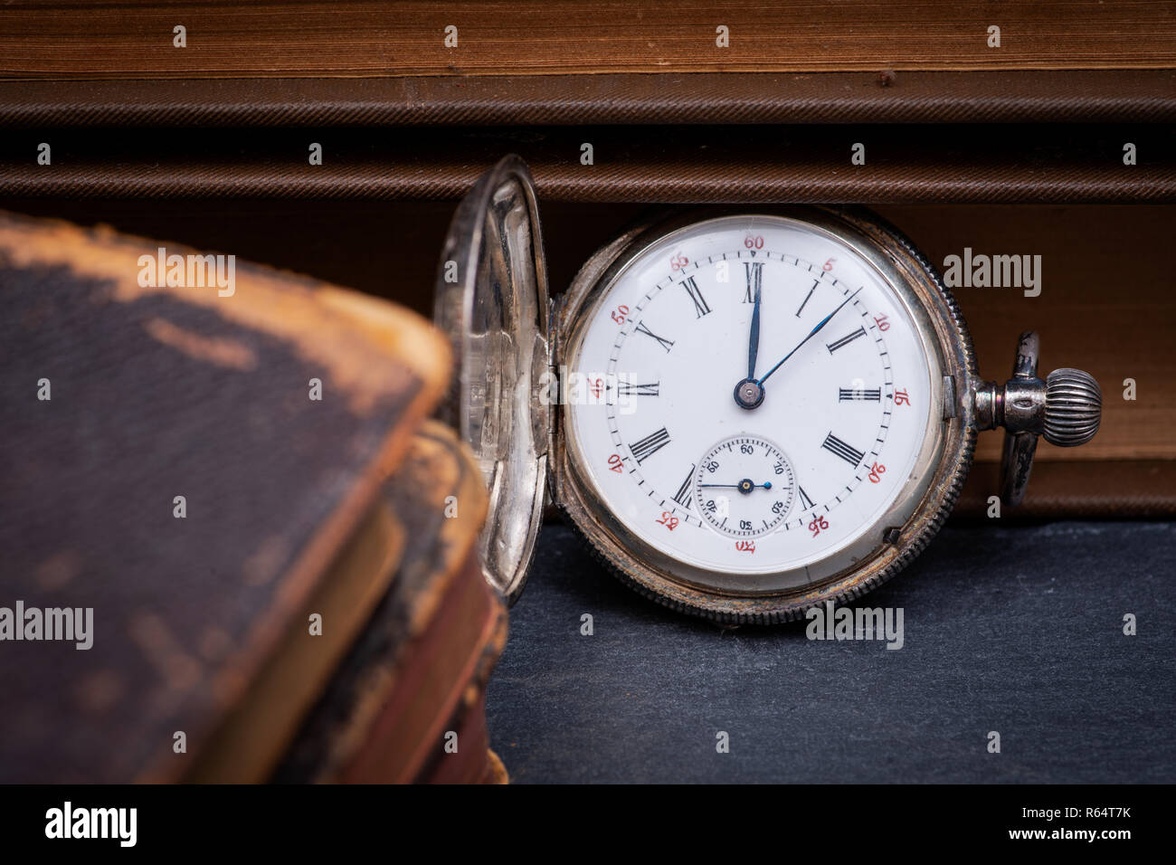 Panta rhei concept: antique pocket watch and pile of vintage hard cover ...