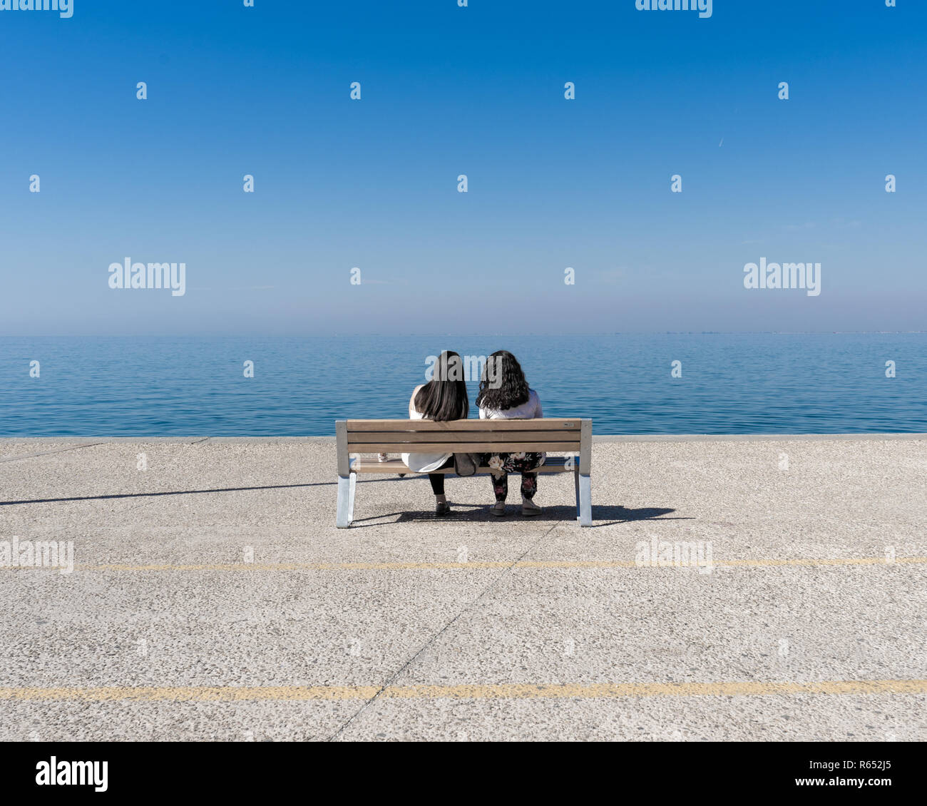 Friends sitting on a bench Stock Photo - Alamy
