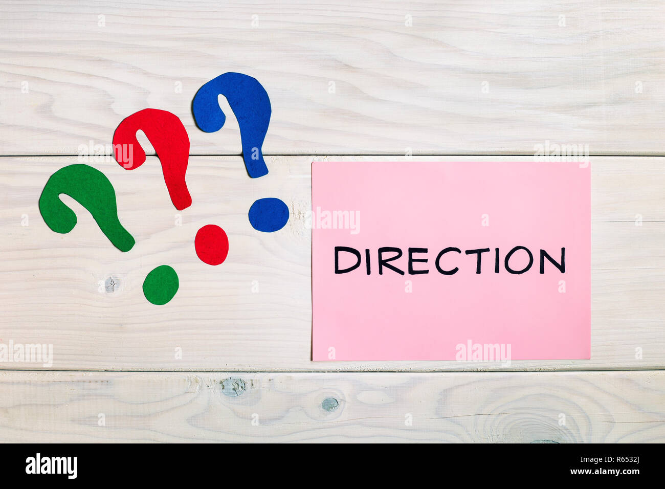 Word direction and question marks on wooden table, which way to go in ...