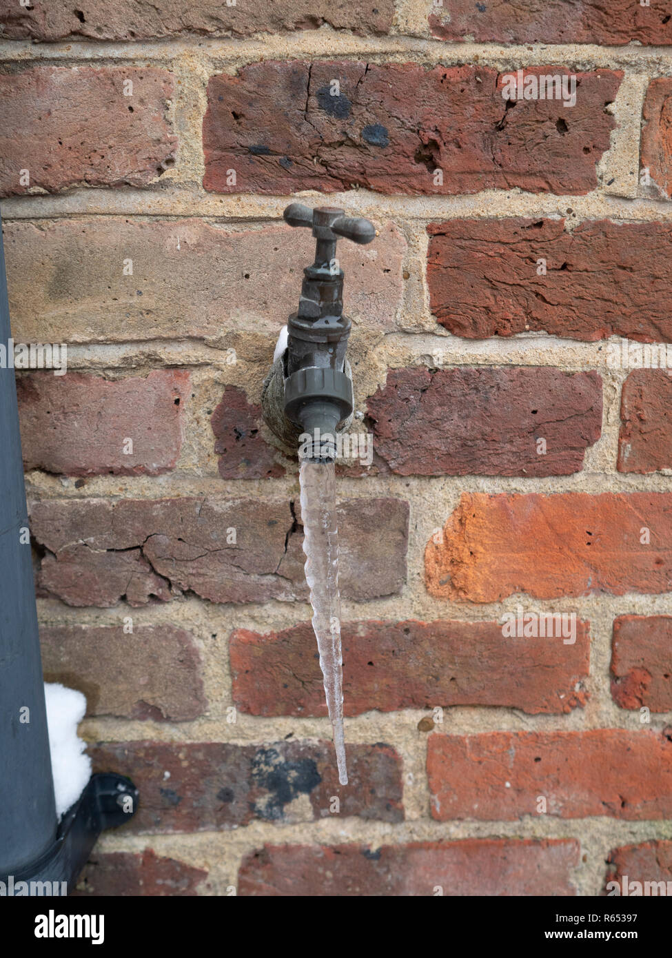Icicle forms under garden wall outdoor tap duing cold spell Stock Photo ...