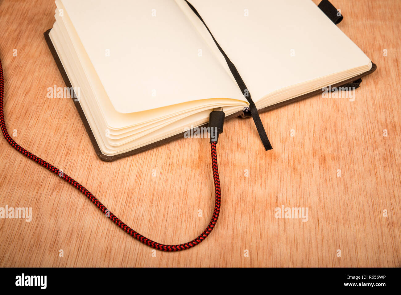 Small paper notebook with a battery charging cable, a concept of analog ...