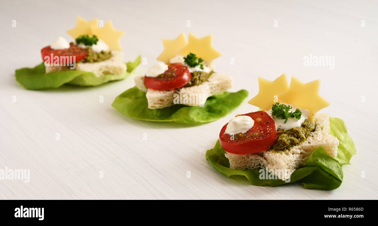 creative party canapes on lettuce with tomato, pesto and cheese in star ...