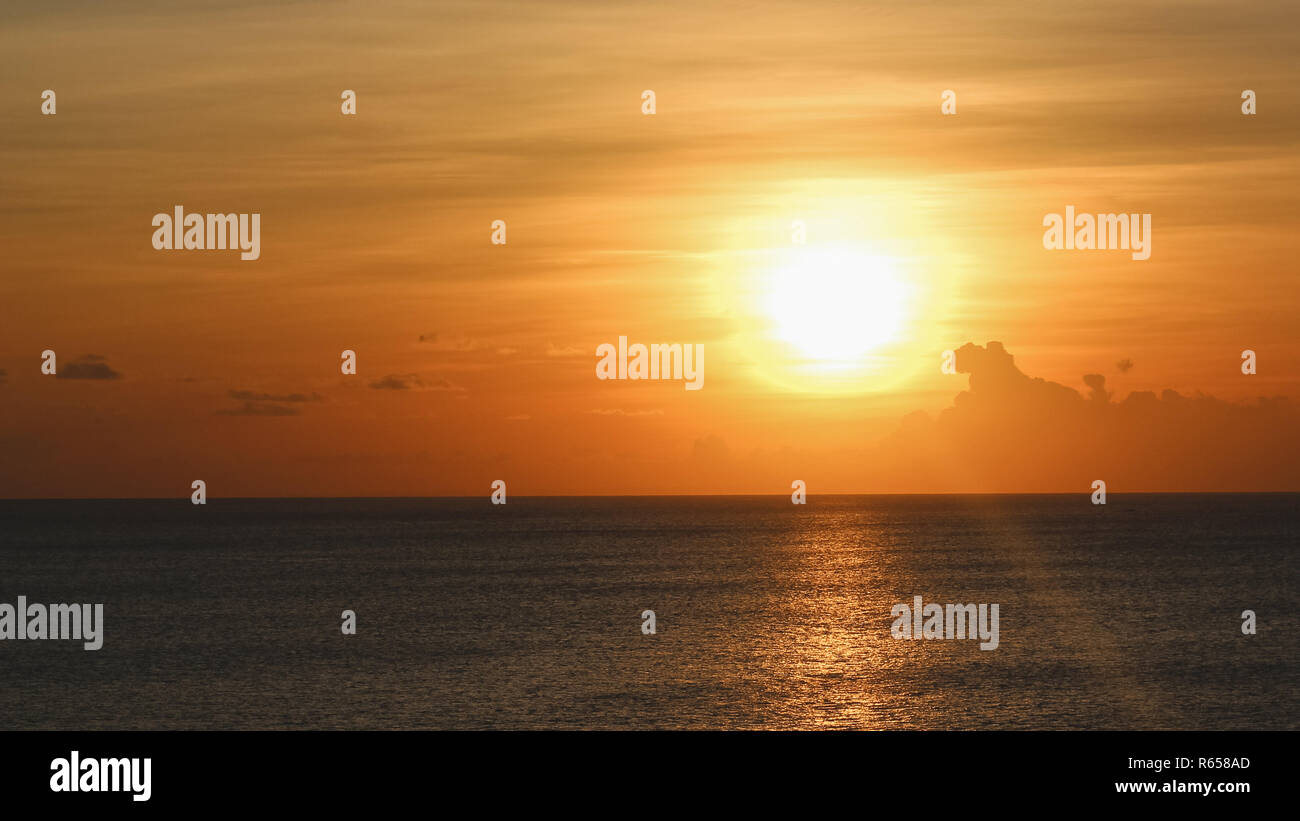 Orange sunset with huge sun and some clouds in Bali Stock Photo - Alamy