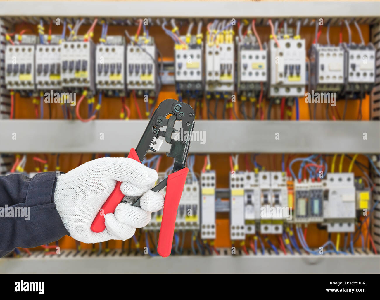Hand in glove holding wire stripper with control panel cabinet Stock ...