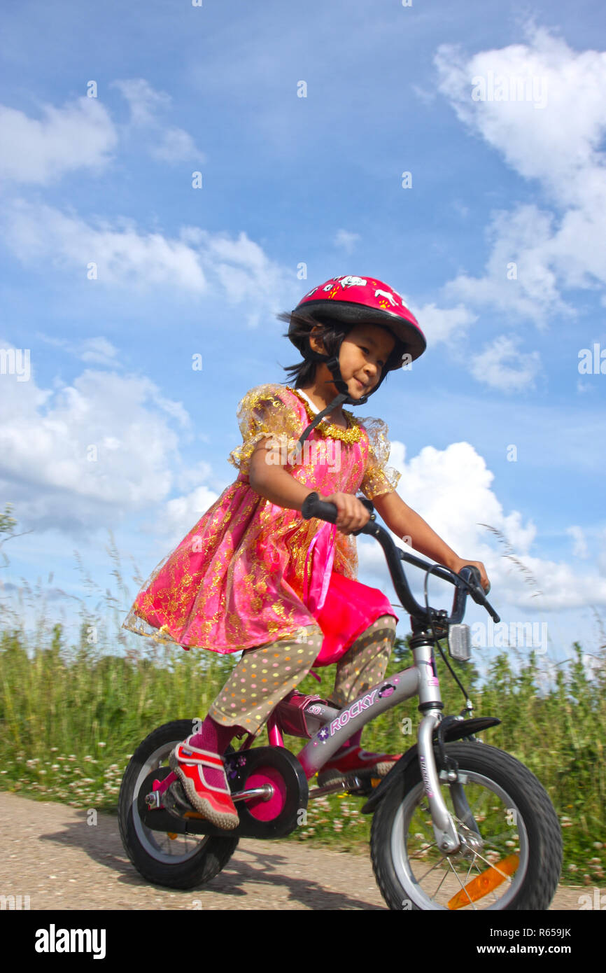 Cute girl cycling with a princess outfit in denmark Stock Photo - Alamy