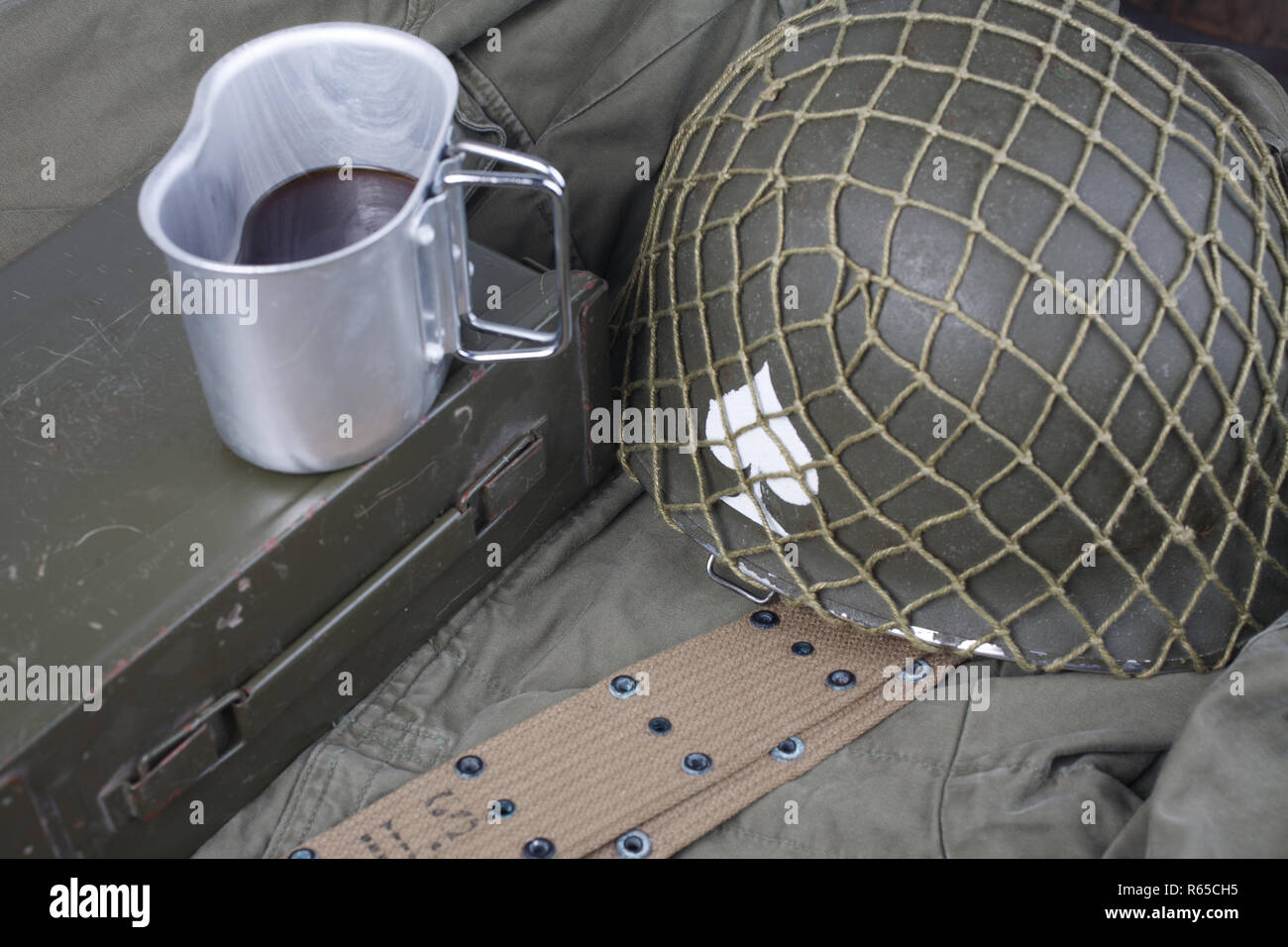a cup of coffee with ww2 period us army military equipment on green ...
