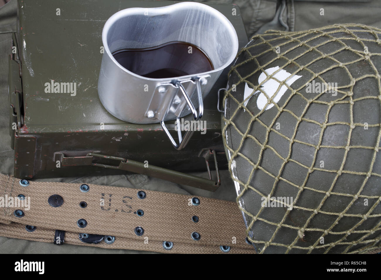 a cup of coffee with ww2 period us army military equipment on green ...