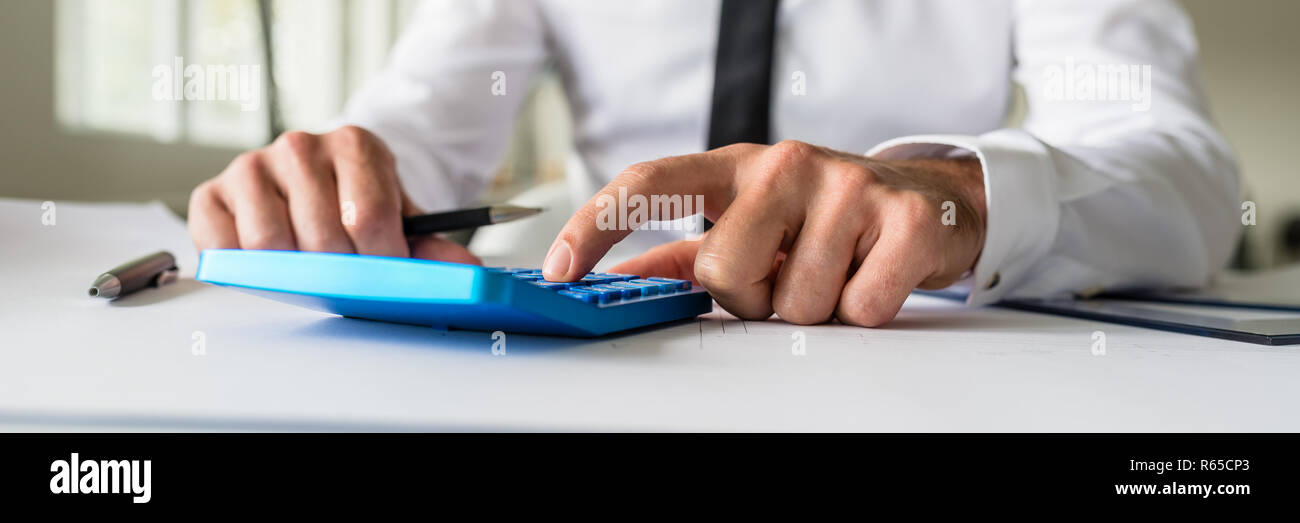 Wide View Image Of Business Engineer Sitting At His Office Desk Working On A Project Calculating