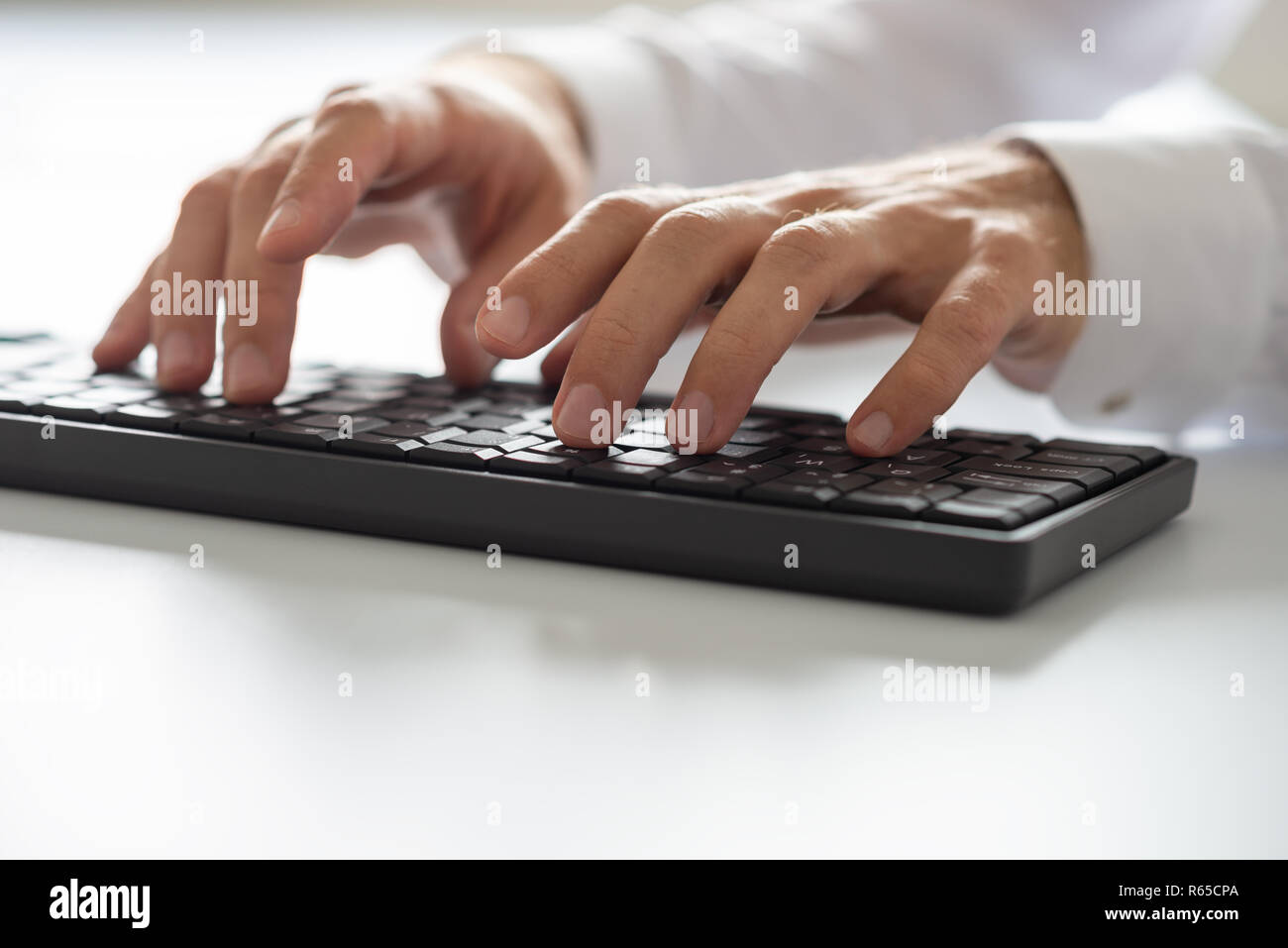 Closeup of computer programmer typing on black computer keyboard as he ...
