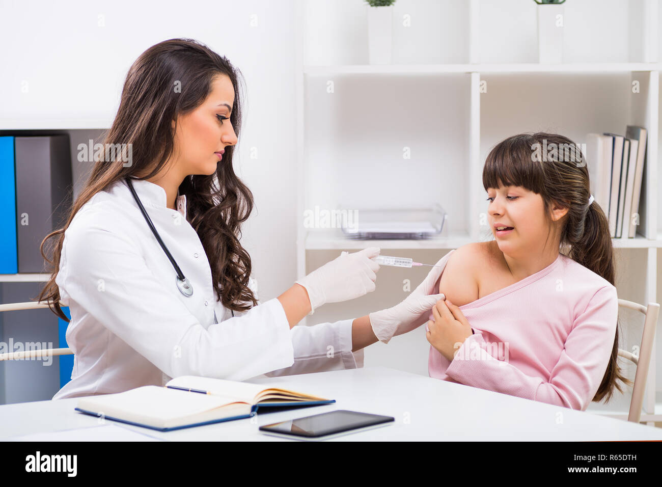 Female doctor giving injection to a scared child at medical office ...