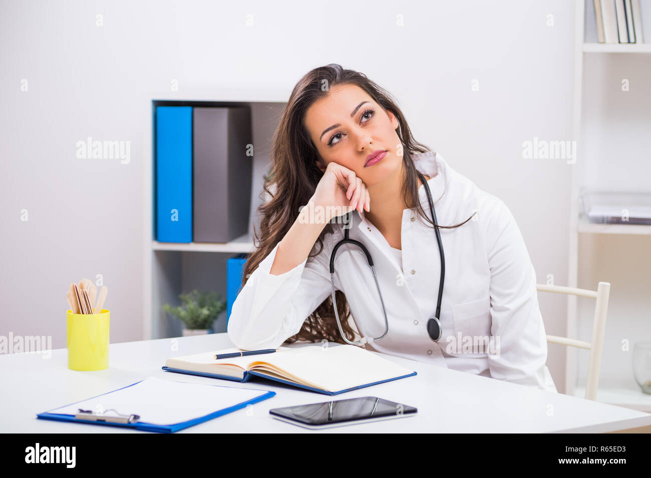 Sad female doctor sitting at her office Stock Photo - Alamy