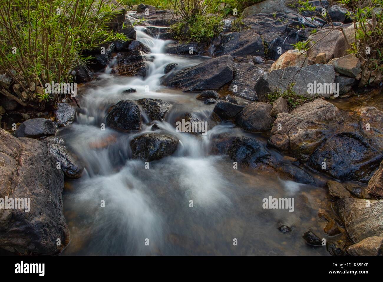 A landscape slow exposure river scene with large boulders and lush ...