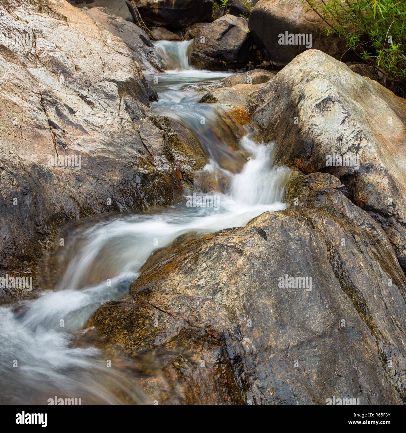 Waterfall river scene with large boulders and lush vegetation green in ...