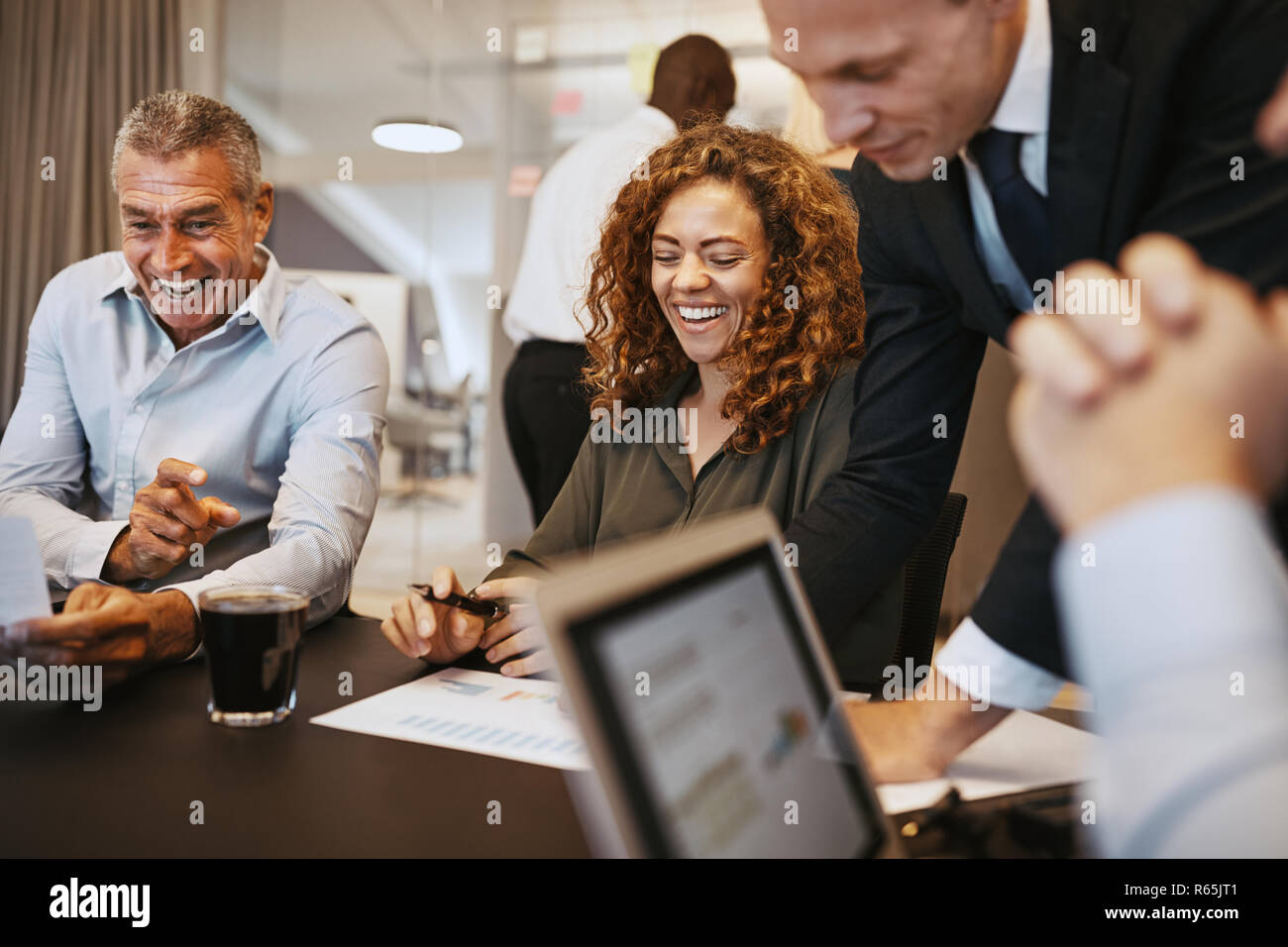 Young businesswoman laughing while sitting with a diverse group of work ...