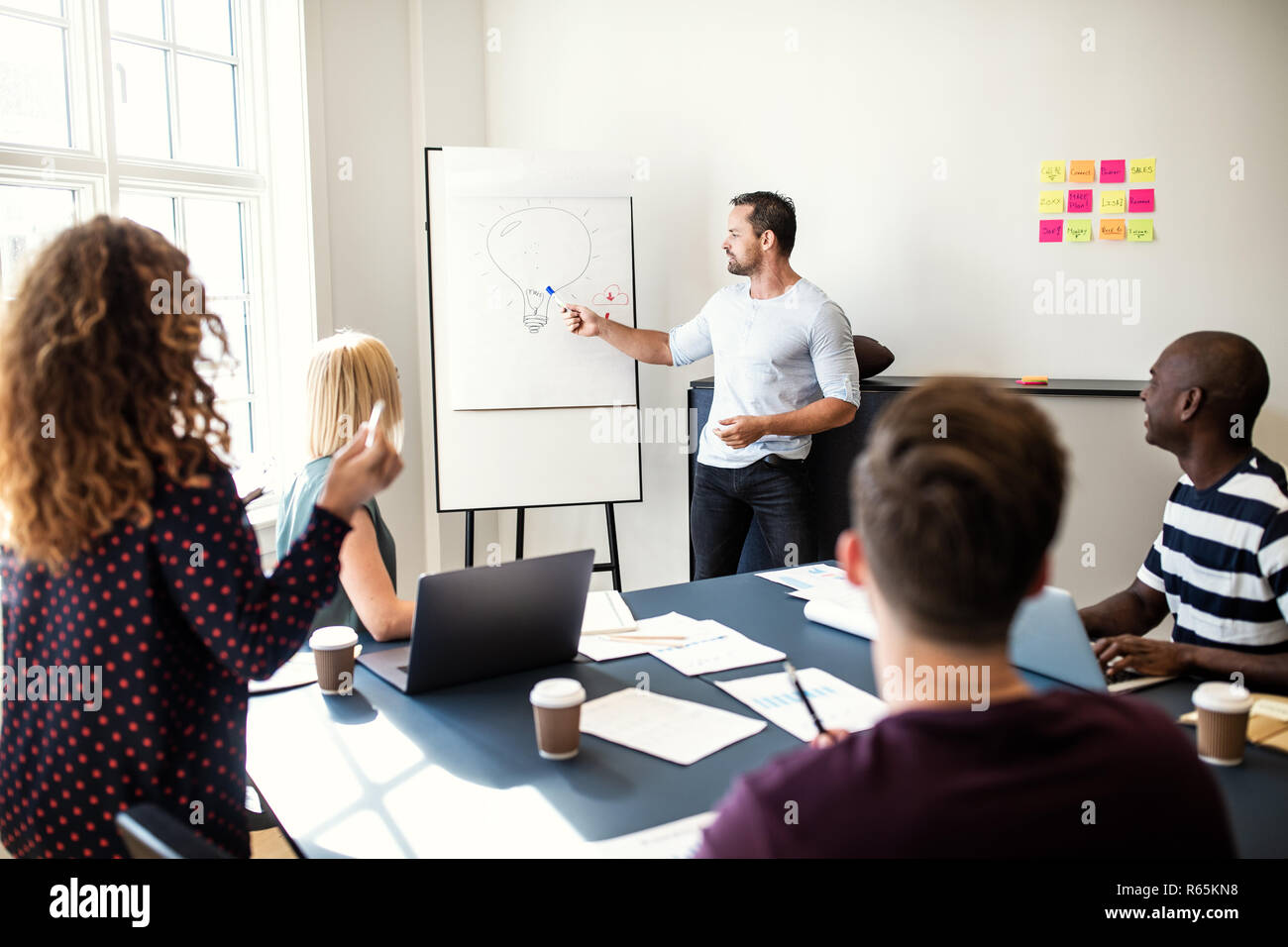 Manager explaining a concept during a whiteboard presentation to a ...