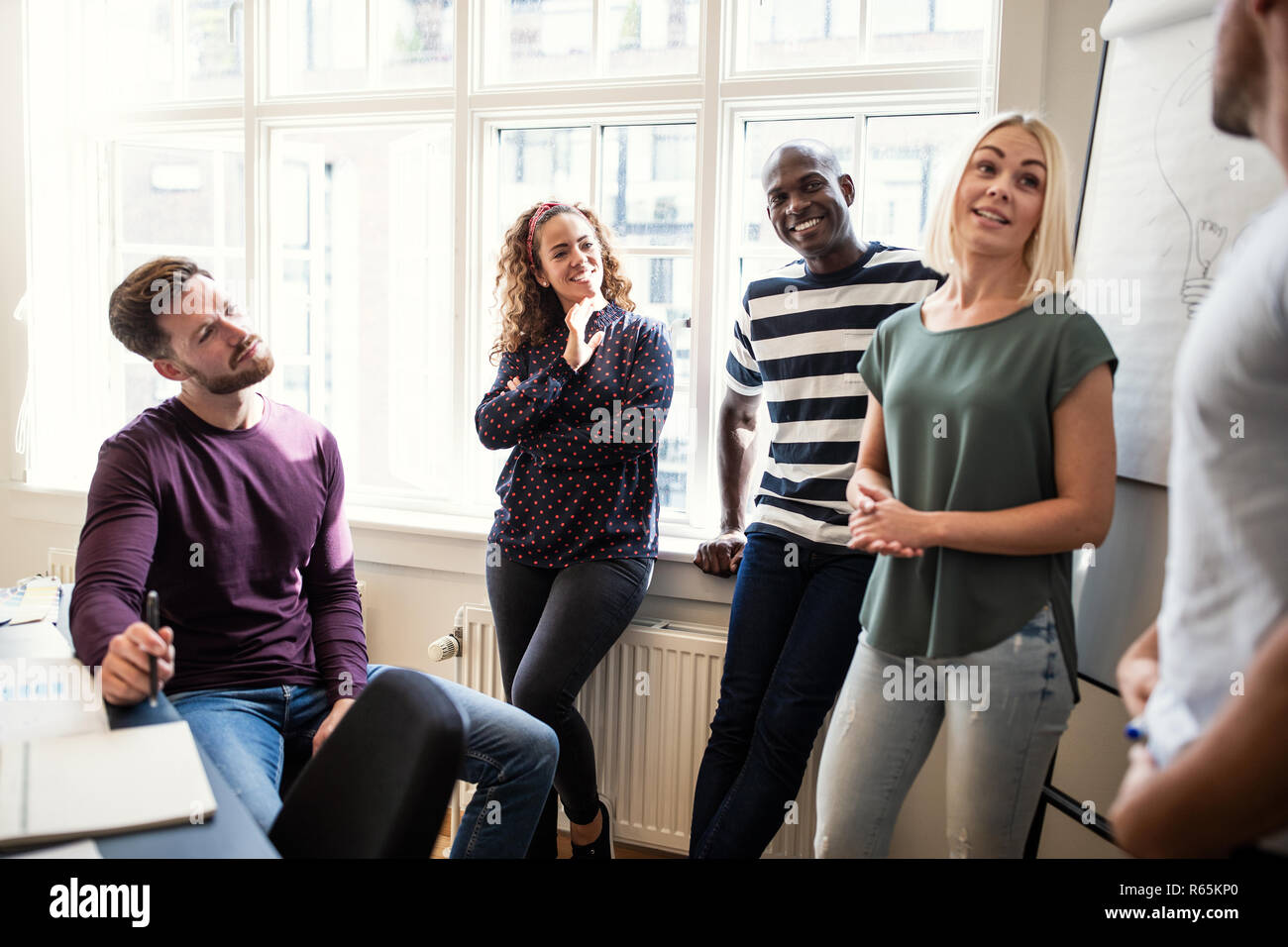 Smiling group of diverse young designers talking together in an office ...