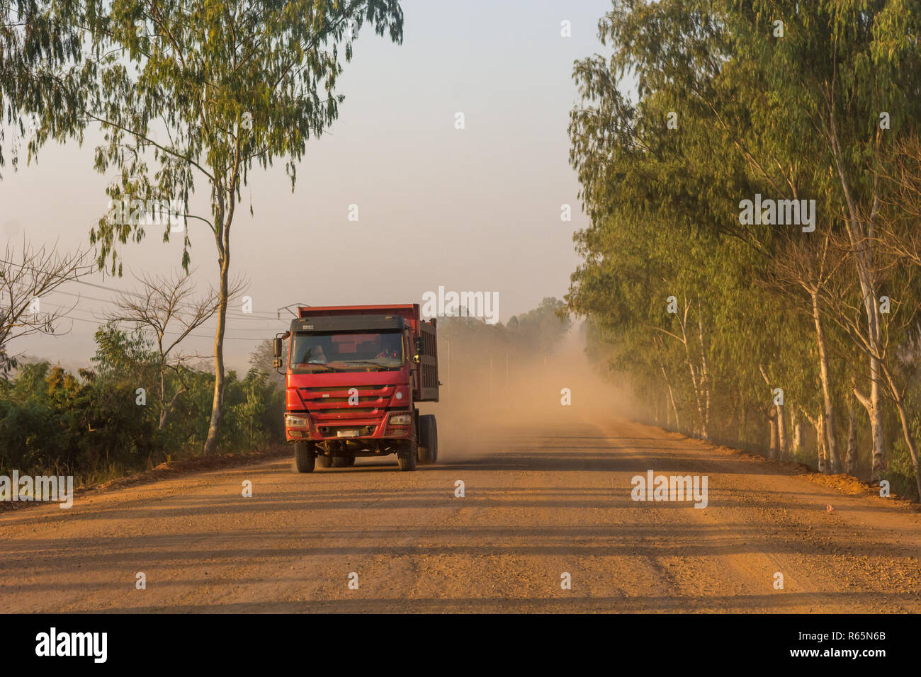 Truck speeding along dirt road across savannah and lifting large amount ...