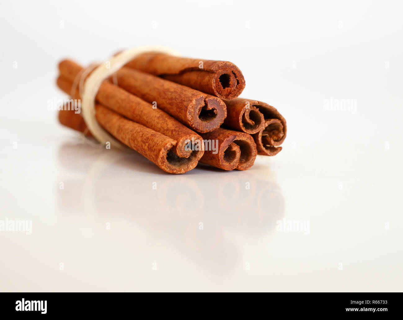 Cinnamon sticks on white reflective background Stock Photo - Alamy
