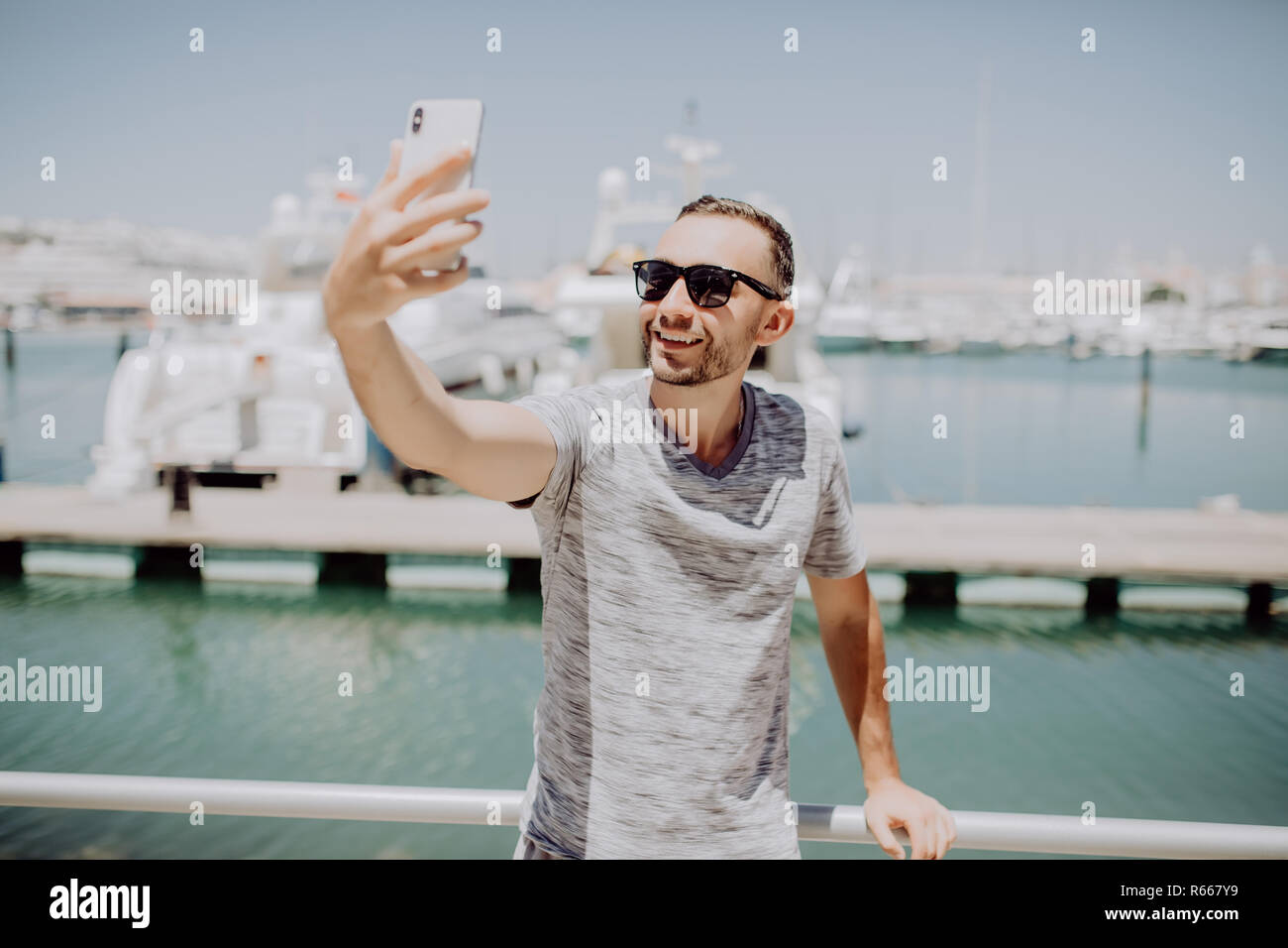 Young handsome man in sunglasses take selfie mobile phone on summer ...