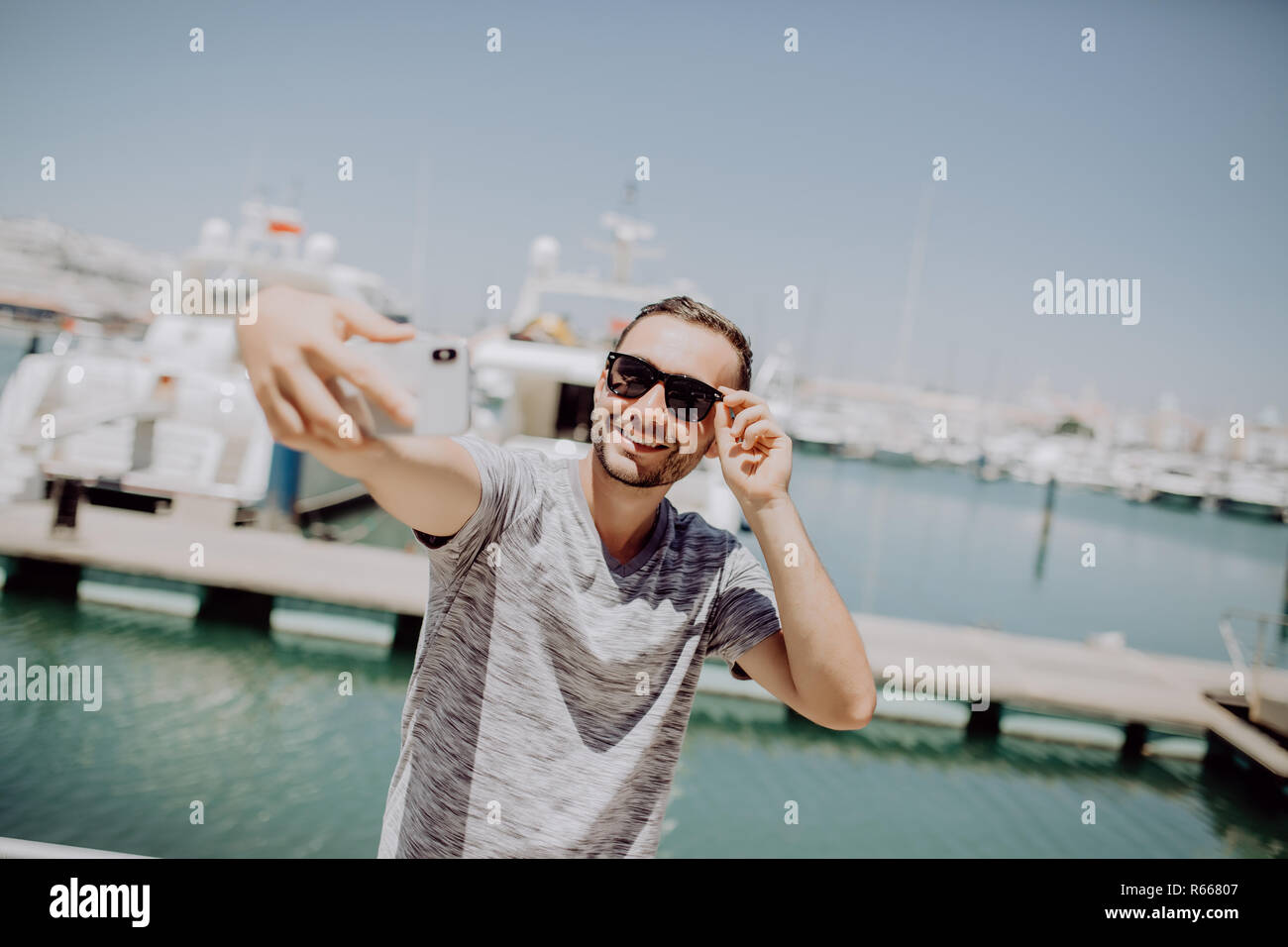 Young handsome man in sunglasses take selfie mobile phone on summer ...