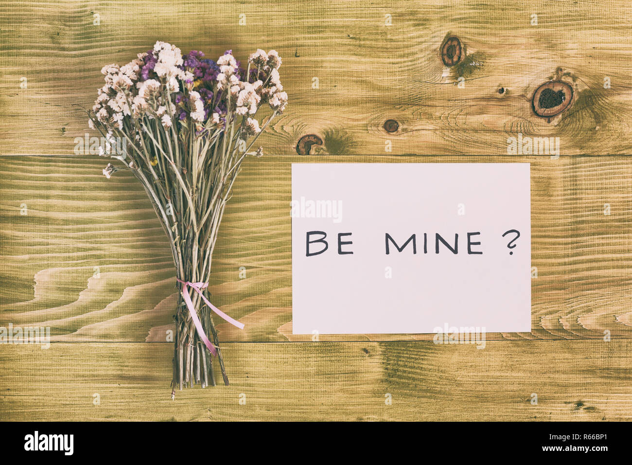 Bouquet of flowers and paper with question be mine on wooden table ...