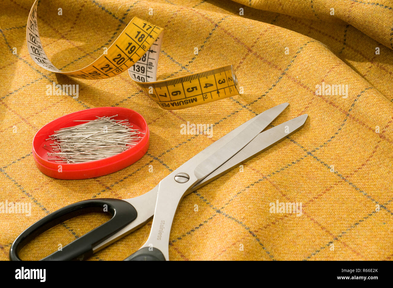 a piece of fabric, scissors, tape measure and pins on the tailor's ...