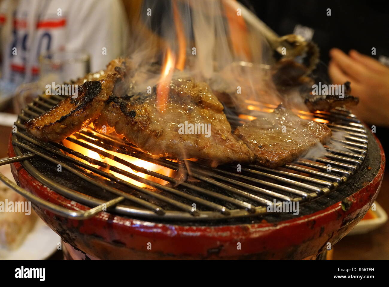 Pieces of nearly cooked pork smoking and being cooked on a charcoal ...