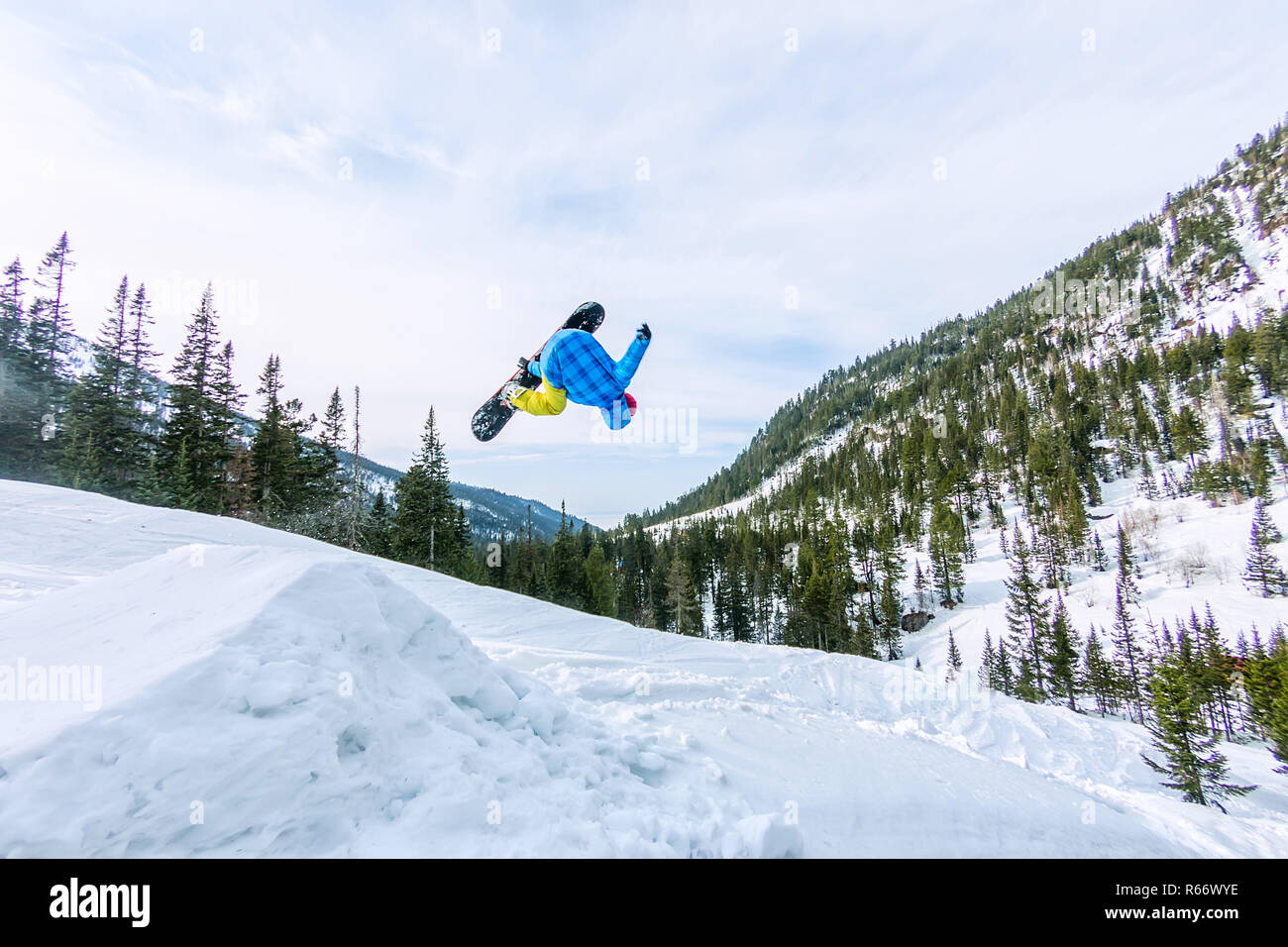 Snowboarder freerider jumping from a snow ramp in the sun on a ...