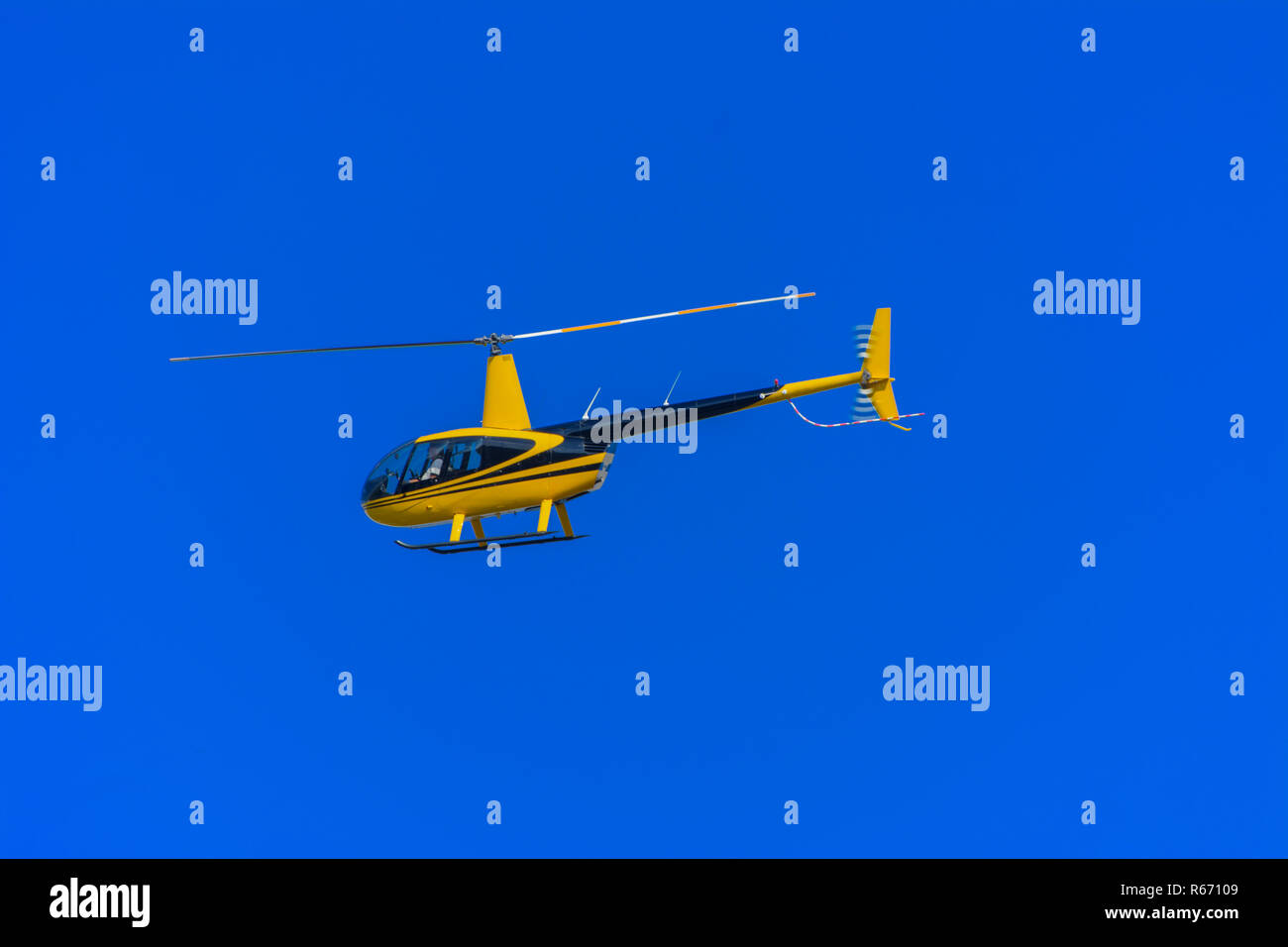 Yellow private helicopter in flight against the background of a bright ...